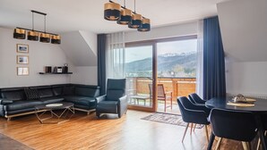 Uma sala de estar moderna com sofá seccional, mesa de jantar com cadeiras e varanda com vista para as montanhas.