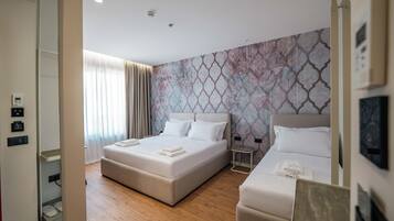 Quarto de hotel moderno com uma cama grande, uma cama menor e um closet espaçoso.