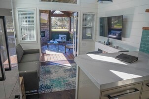 Cozinha moderna com TV integrada, área de refeições com assentos externos e vista para o pátio.