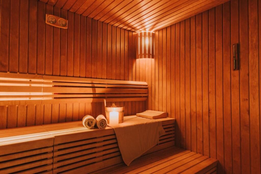 Uma sauna de madeira com bancos, um aquecedor de banco e uma vela.