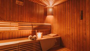 Uma sauna de madeira com bancos, um aquecedor de banco e uma vela.