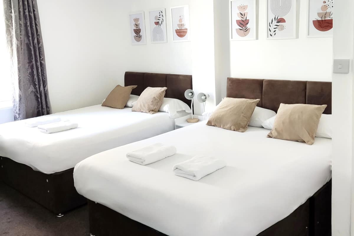 Quarto de hotel com duas camas, uma luminária no teto e obras de arte nas paredes.