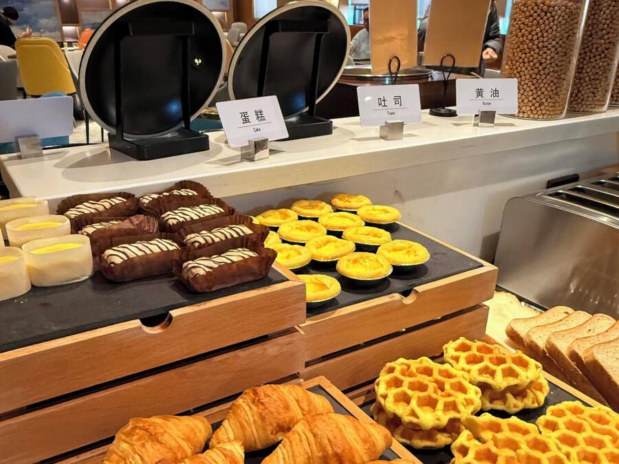 Vitrine de pastelaria com diversos doces e uma máquina de waffles.