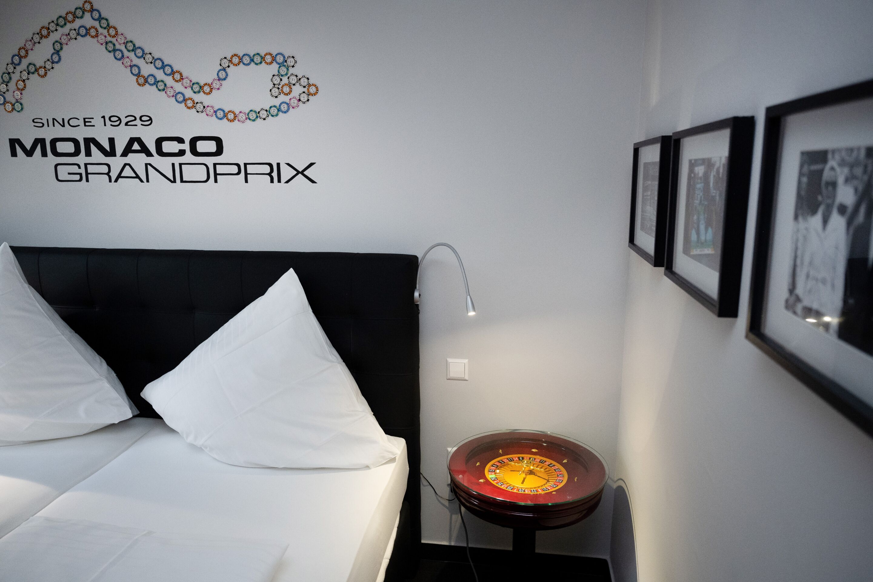Quarto de hotel com cama, relógio de parede e quadros emoldurados.
