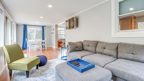 Uma sala de estar moderna com um sofá seccional cinza, uma poltrona verde e um banquinho azul.