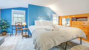 Um quarto com cama, escrivaninha, cadeira, luminária e planta em vaso.