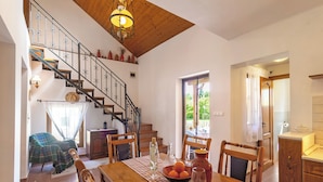 Uma sala de jantar com uma mesa de madeira, cadeiras, uma escada e vista para o exterior.
