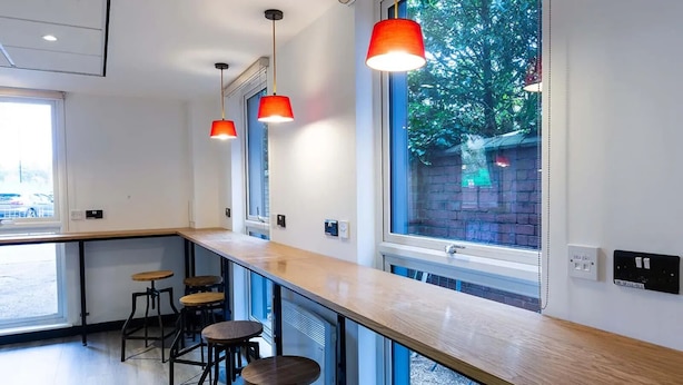 Cozinha moderna com bancada comprida, banquetas e luminárias pendentes.