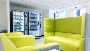 Uma área de espera moderna com assentos amarelo vibrante e máquinas de venda automática.