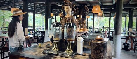 Uma área de bar com balcão de madeira, banquetas e uma escultura decorativa.
