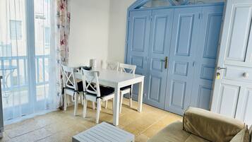 Quarto com mesa de jantar, cadeiras, sofá e porta arqueada azul.
