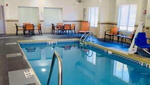 Piscina com água azul cristalina, escada de piscina e área de estar com cadeiras.