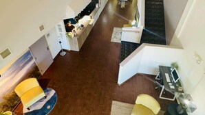 Um hall de hotel com balcão de recepção, área de estar e escadaria.