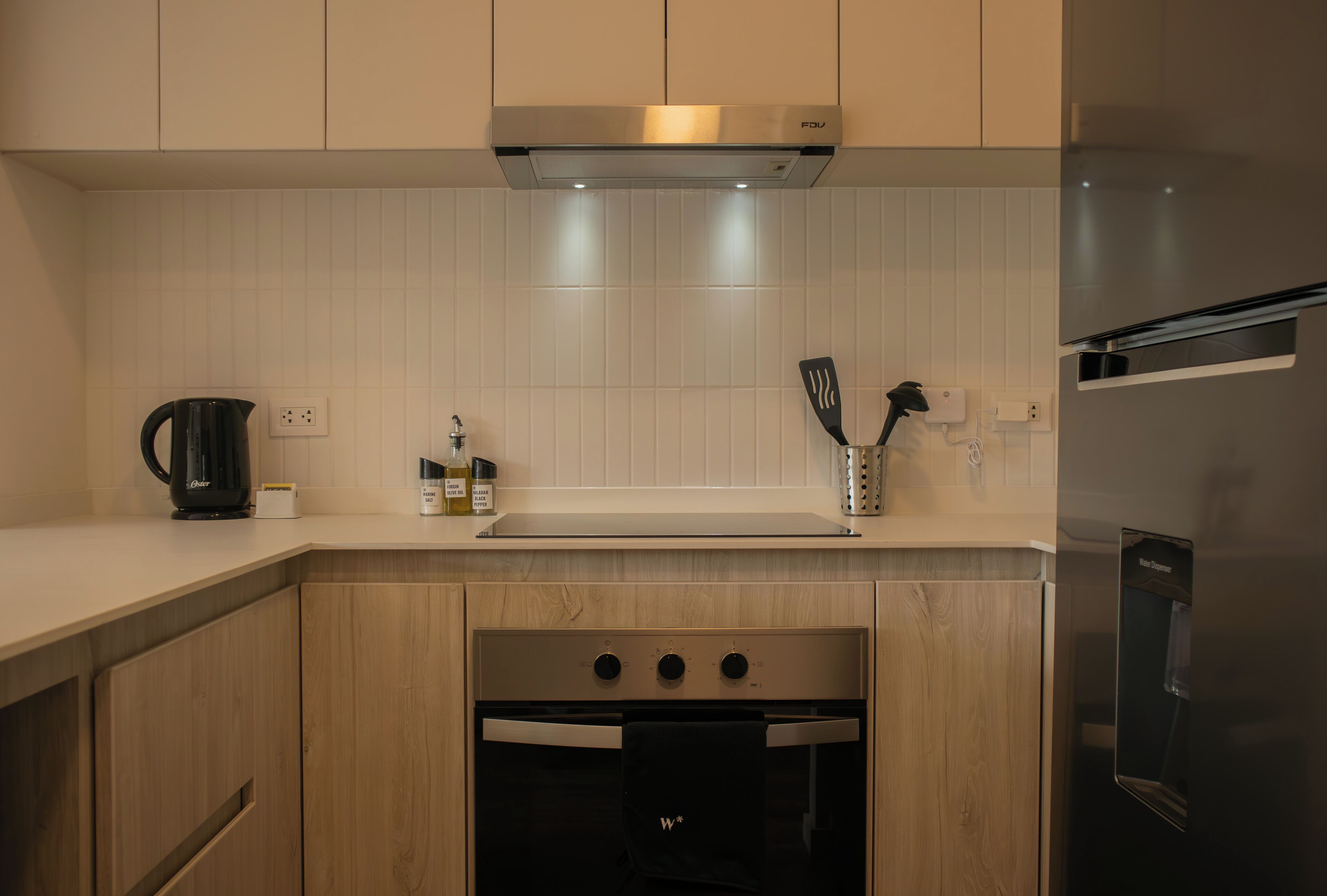 Uma cozinha moderna com armários de madeira, forno embutido, geladeira de aço inoxidável e cafeteira.