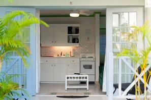 Uma cozinha moderna com armários brancos, uma mesa pequena e um ventilador de teto.