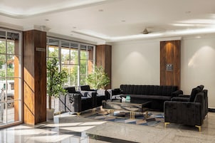 Um lobby moderno com um sofá de couro preto, uma mesa de centro e um vaso de planta.