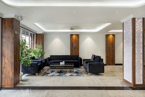 Um lobby moderno com um sofá modular preto, uma mesa de centro e um painel decorativo.