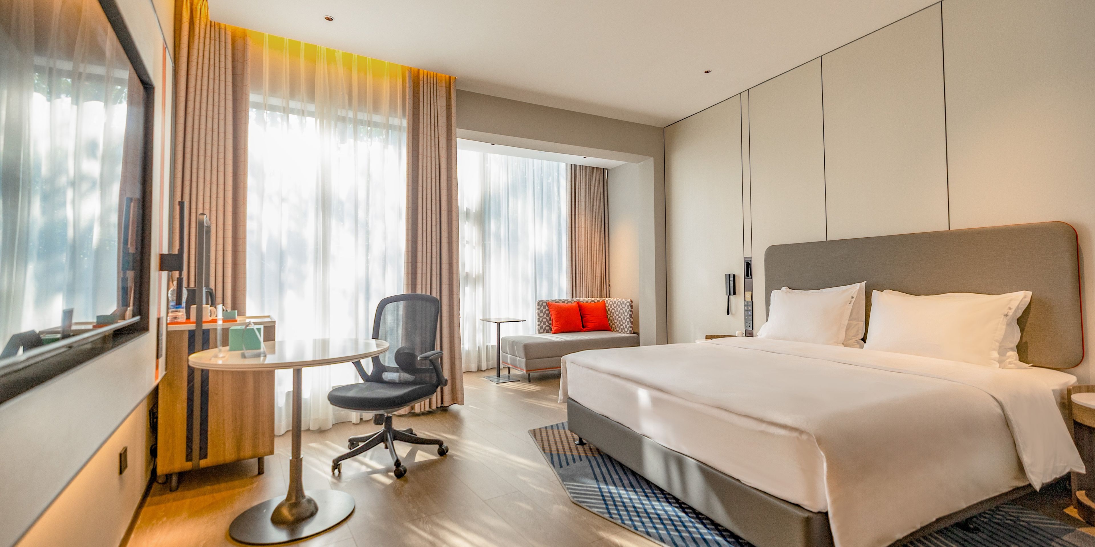Quarto de hotel com uma cama grande, uma escrivaninha, uma cadeira e um sofá.