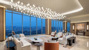 Um hall amplo com móveis modernos, grandes janelas com vista para a cidade e um lustre de design exclusivo.