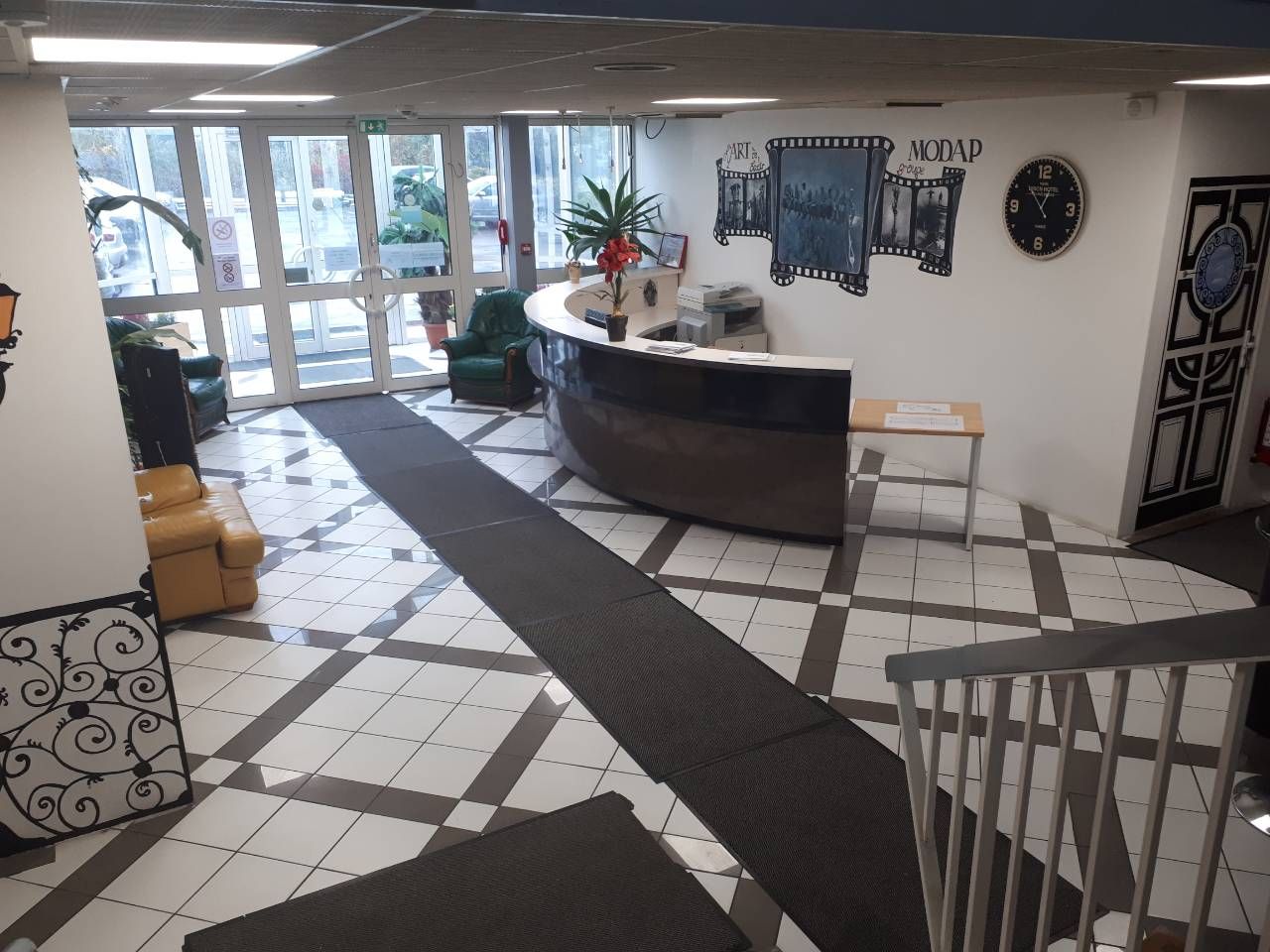 Uma área de recepção com balcão de check-in, um relógio e uma janela grande.