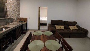 Um espaço de estar moderno com cozinha, área de refeições e um conjunto de sofás.