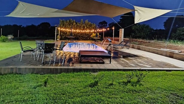 Área de varanda externa com um amplo toldo, uma banheira de hidromassagem e luzes de Natal.