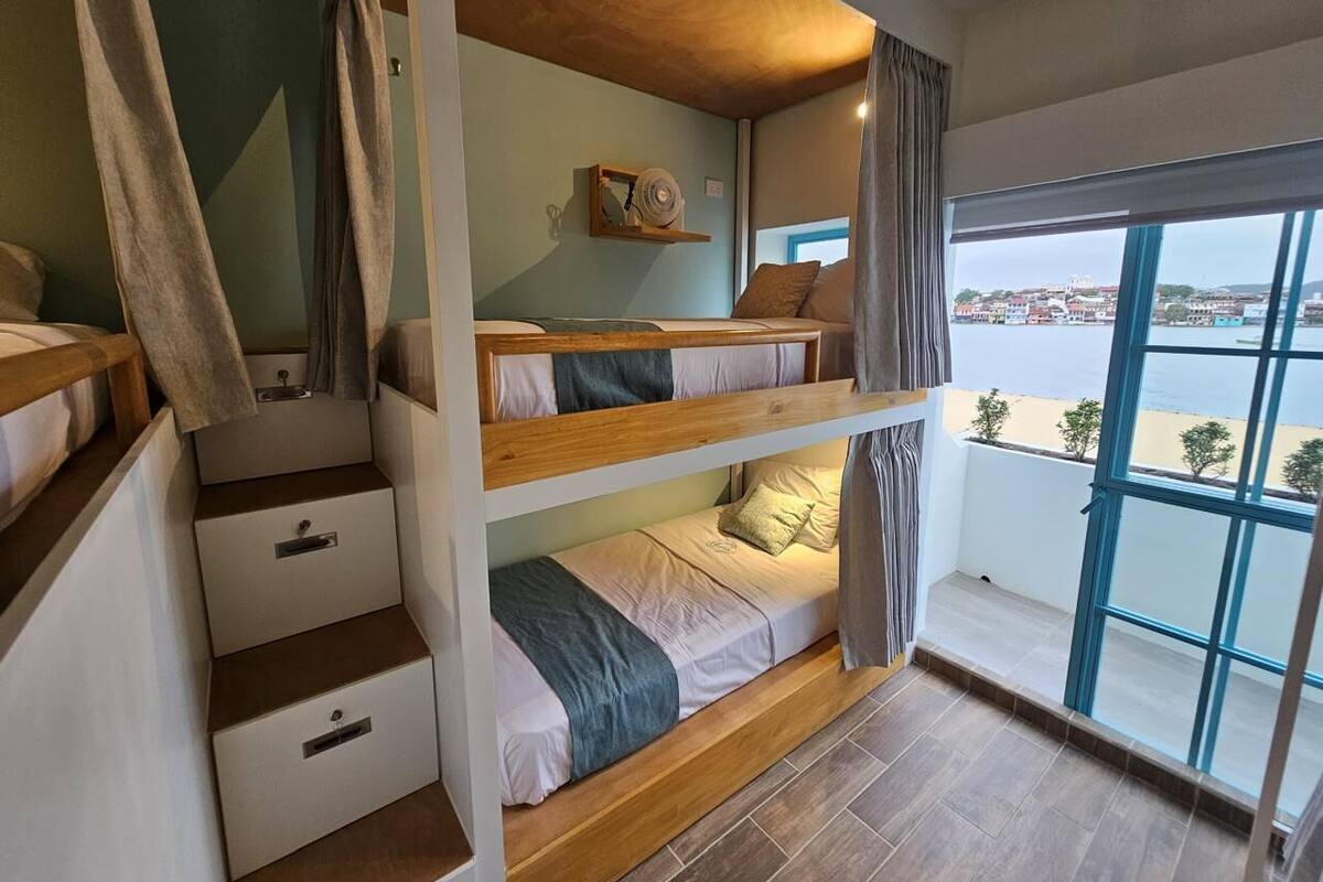 Quarto com vários níveis, beliches, um pequeno espaço para prateleiras e vista para a água.