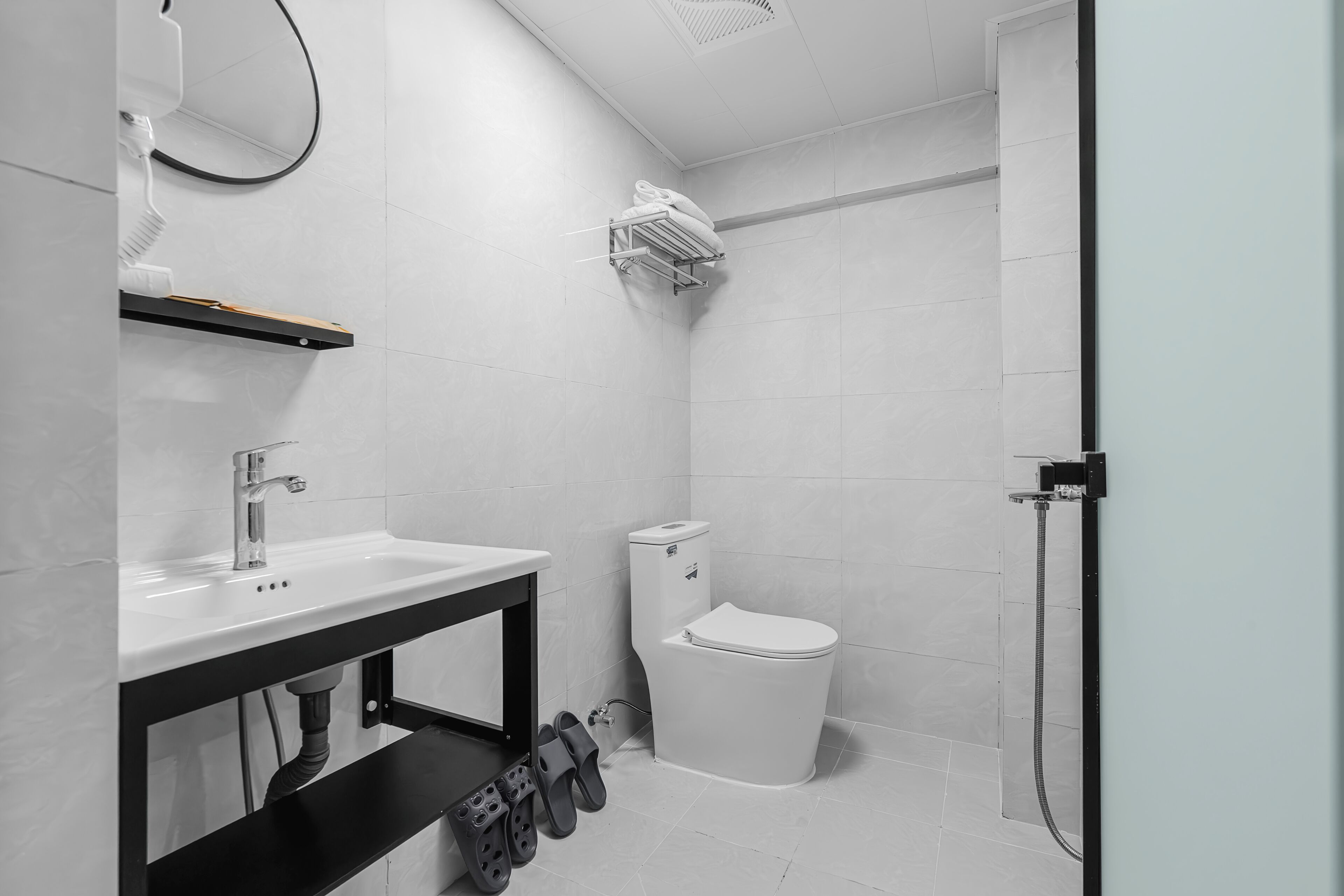 Uma casa de banho moderna com lavatório, sanita e chuveiro brancos.