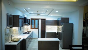 Cozinha moderna com ilha central, eletrodomésticos embutidos e ventilador de teto.