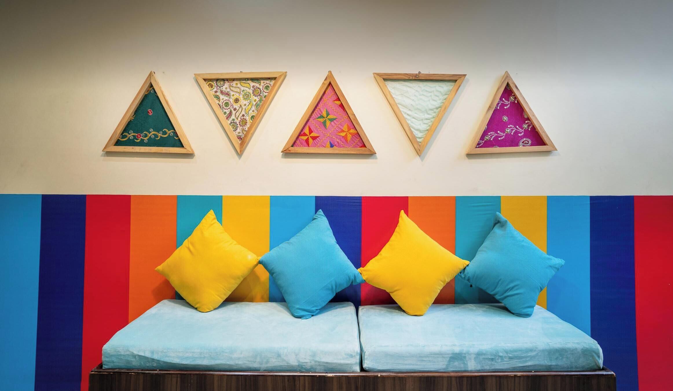 Uma cama com almofadas coloridas e uma parede com obras de arte emolduradas.