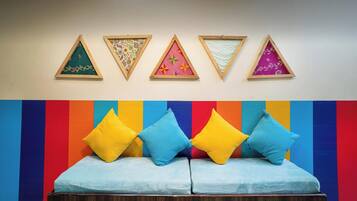 Uma cama com almofadas coloridas e uma parede com obras de arte emolduradas.