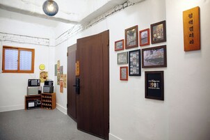 Um quarto com porta de madeira, janela e diversos quadros na parede.