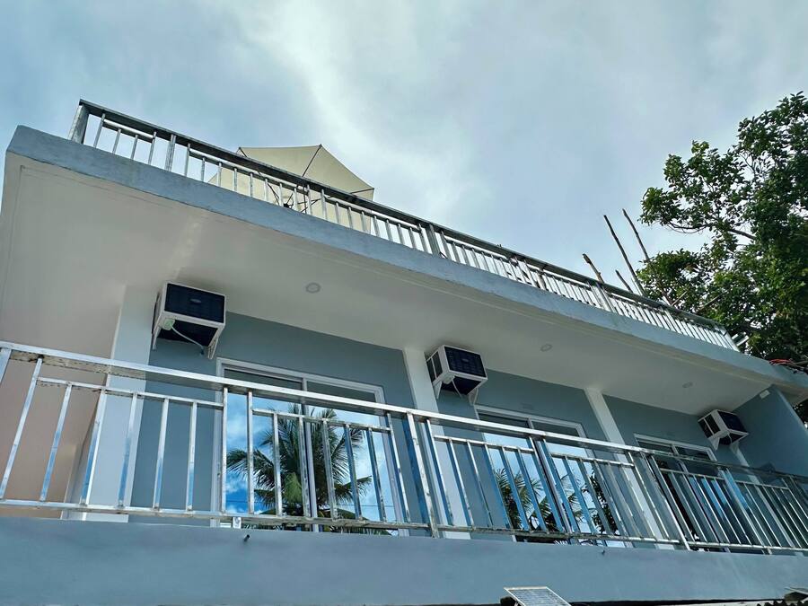 Um edifício com vários andares, varanda, aparelhos de ar condicionado e céu claro.