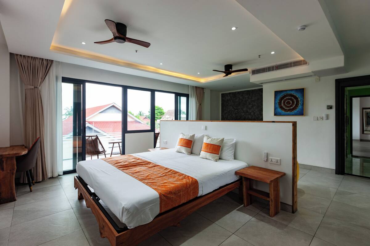 Quarto de hotel moderno com cama grande, cabeceira de madeira e escrivaninha.