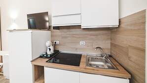 Uma cozinha compacta com fogão embutido, pia e micro-ondas.