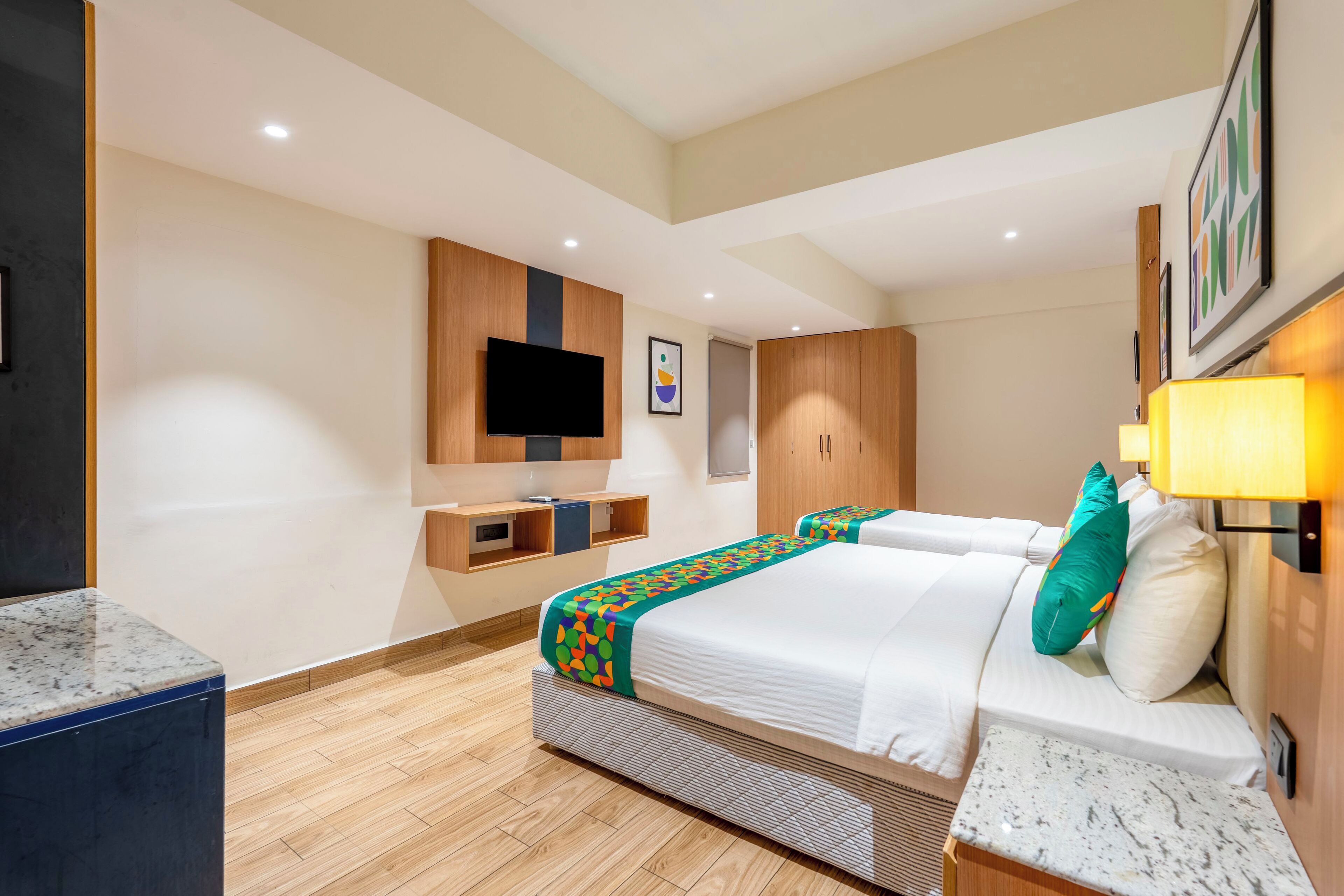 Quarto de hotel com cama, televisão, escrivaninha e banheiro.