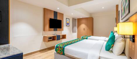 Quarto de hotel com cama, televisão, escrivaninha e banheiro.