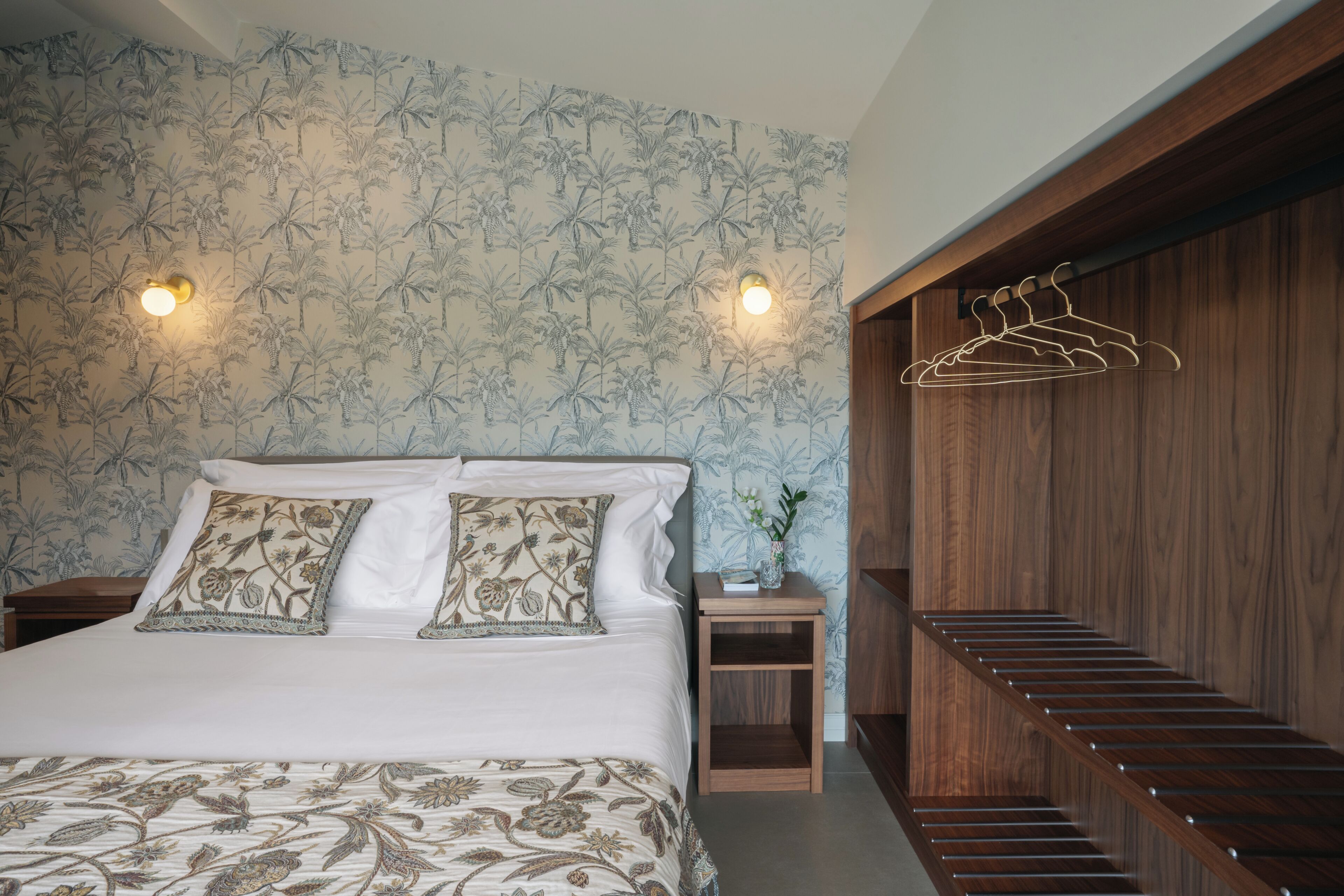 Quarto com cama, duas mesas de cabeceira, um criado-mudo e um armário de madeira, além de escada de madeira.