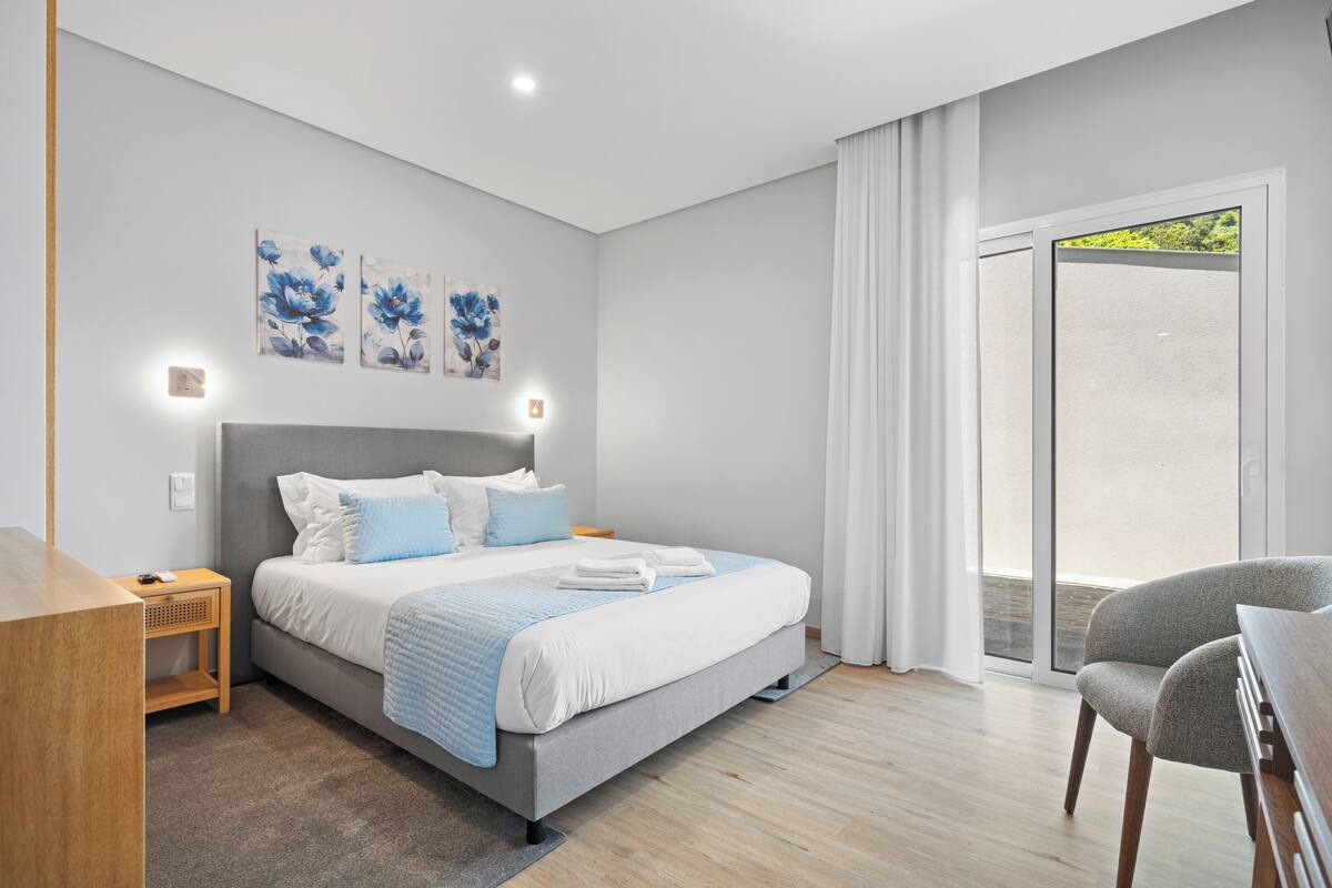 Quarto moderno com cama, mesas de cabeceira, escrivaninha e cadeira.