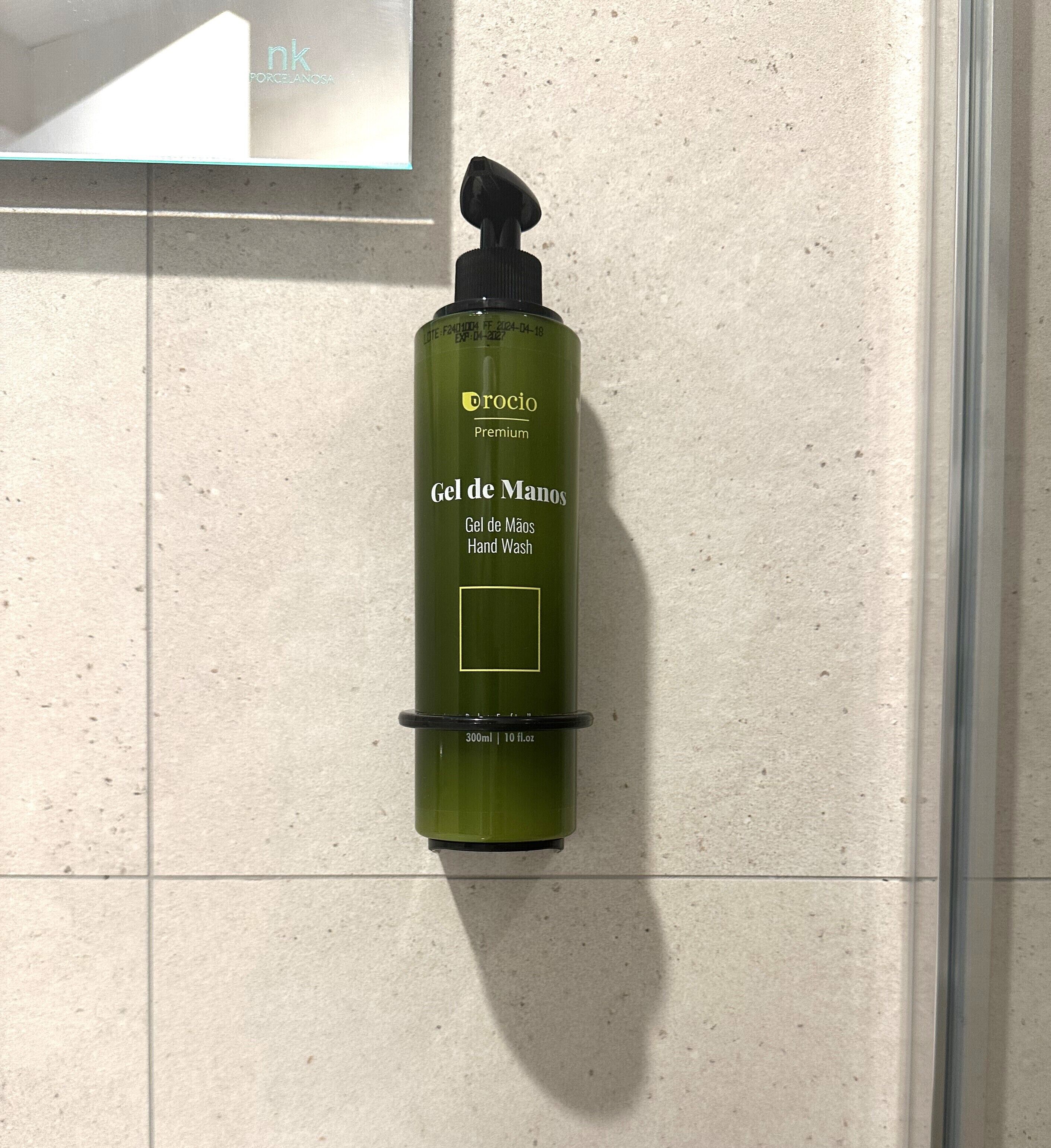 Uma embalagem verde de Drocio Premium Gel de Manos sobre uma parede azulejada.