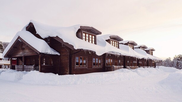 Uma cabana de madeira com várias chaminés, rodeada por neve.