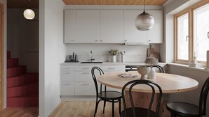 Uma cozinha moderna com armários brancos, uma mesa de jantar de madeira e cadeiras pretas.
