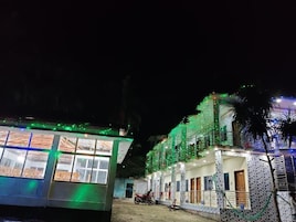 Um edifício com várias janelas e varandas, cercado por vegetação.