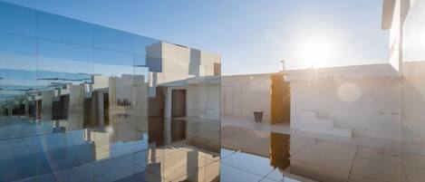 Um edifício moderno com superfícies de vidro refletivas e um céu claro.