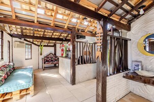 Um interior rústico com teto de madeira, um banco com estofamento floral e uma parede de tijolos brancos.