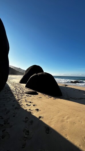 Uma praia com pedras grandes e pegadas na areia.