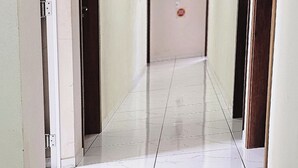 Corredor com sinalização indicando a saída, extintor fixado na parede e uma porta no final.