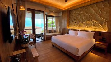Quarto de hotel com uma cama grande, ventoinha no teto, vista para o mar e parede de pedra.