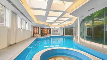 Piscina interna com claraboia e paredes de vidro.