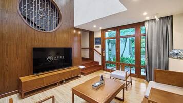 Uma sala de estar moderna com televisão de tela plana, móveis de madeira e uma janela grande com vista para o verde.